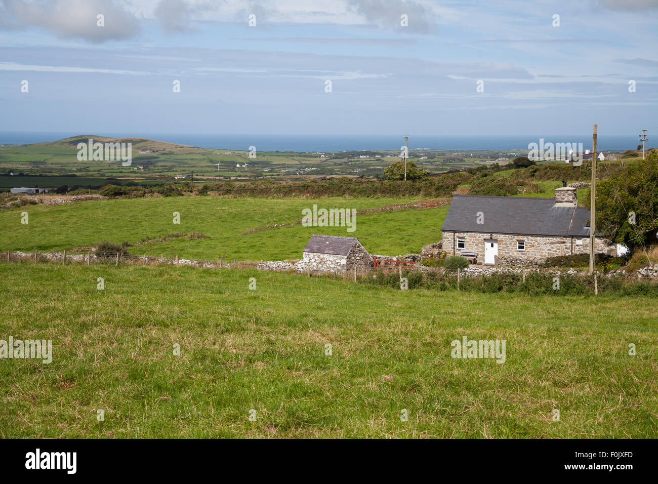 A view across fields towards Ynys Enlli and traditional Welsh cottage ...