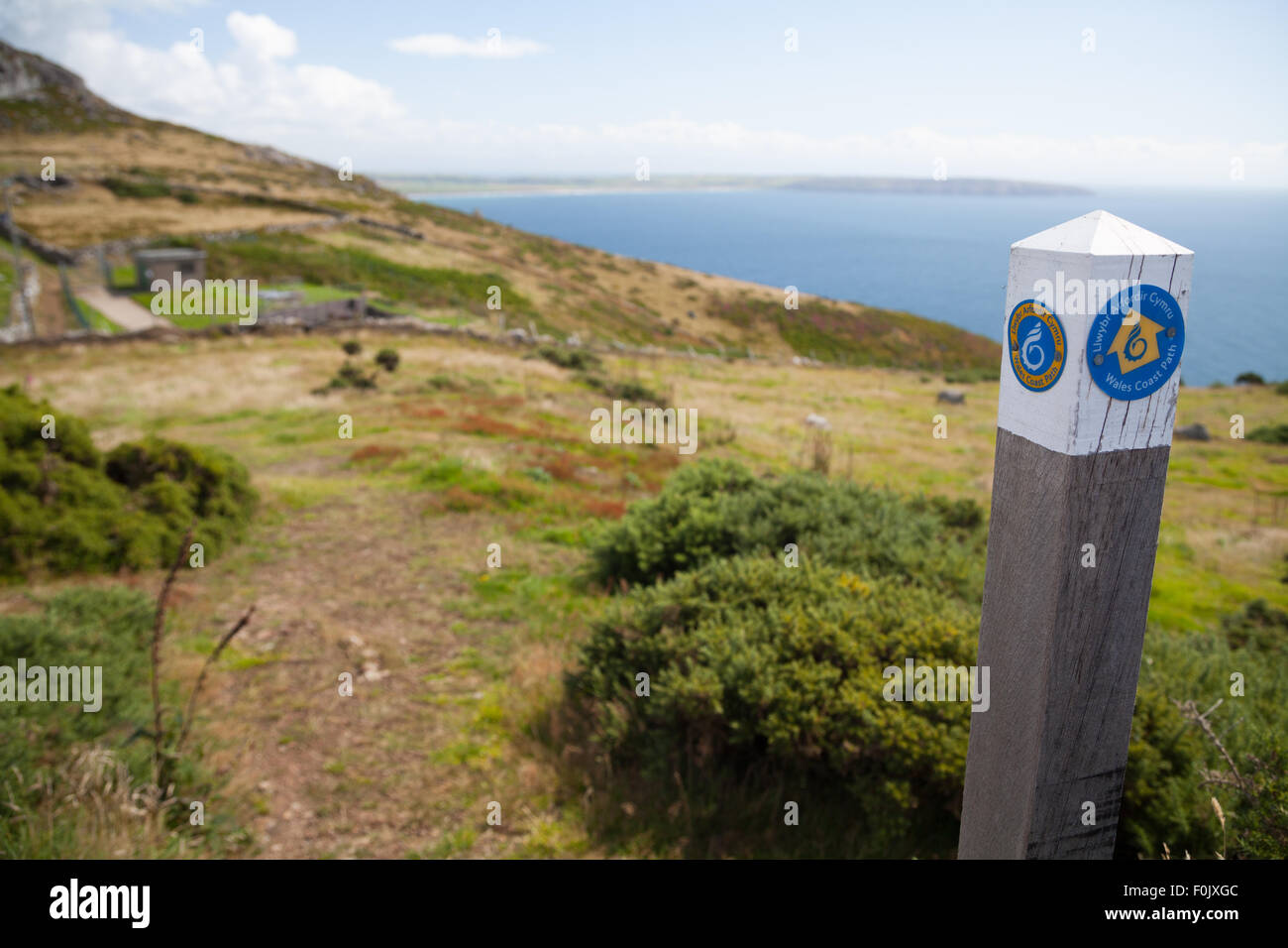 Wales Coast Path waymarker / post at Penarfynydd, Rhiw with the sea and ...