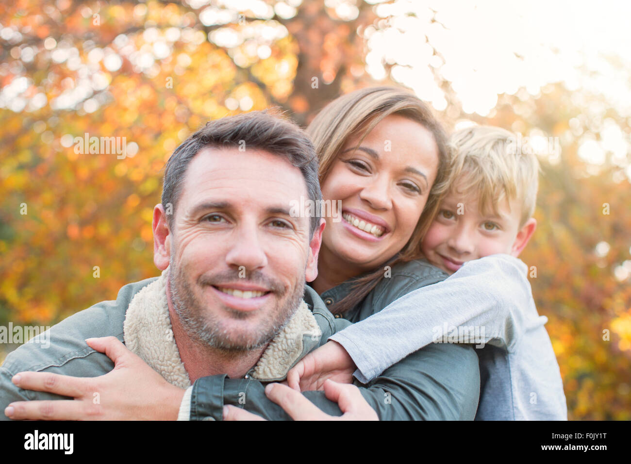Portrait smiling family hugging in front of autumn leaves Stock Photo ...