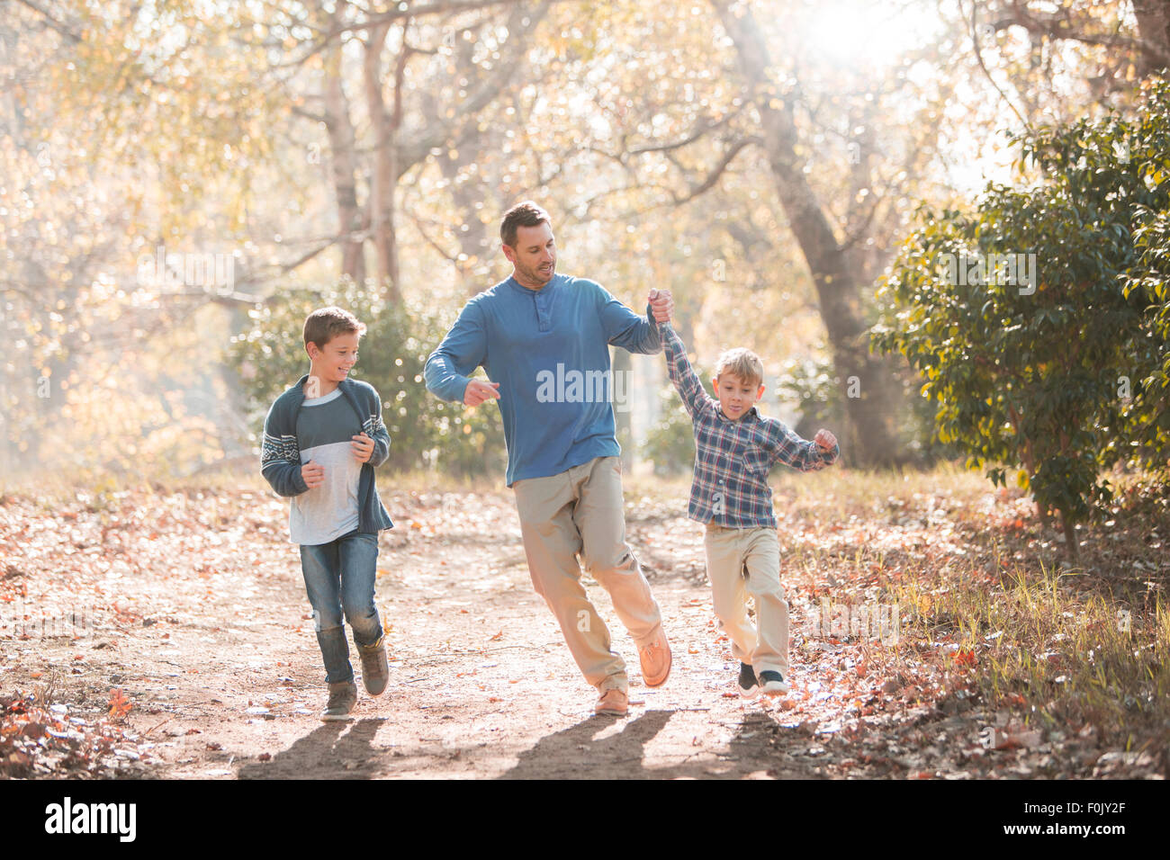 Playful father and sons running on trail in woods Stock Photo - Alamy