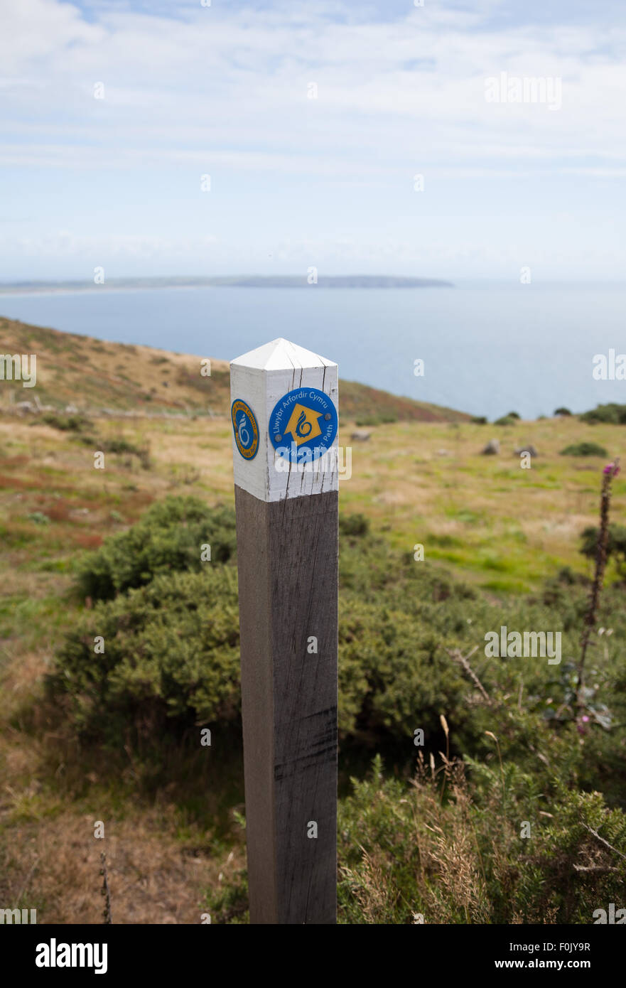 Wales Coast Path waymarker / post at Penarfynydd, Rhiw with the sea and ...