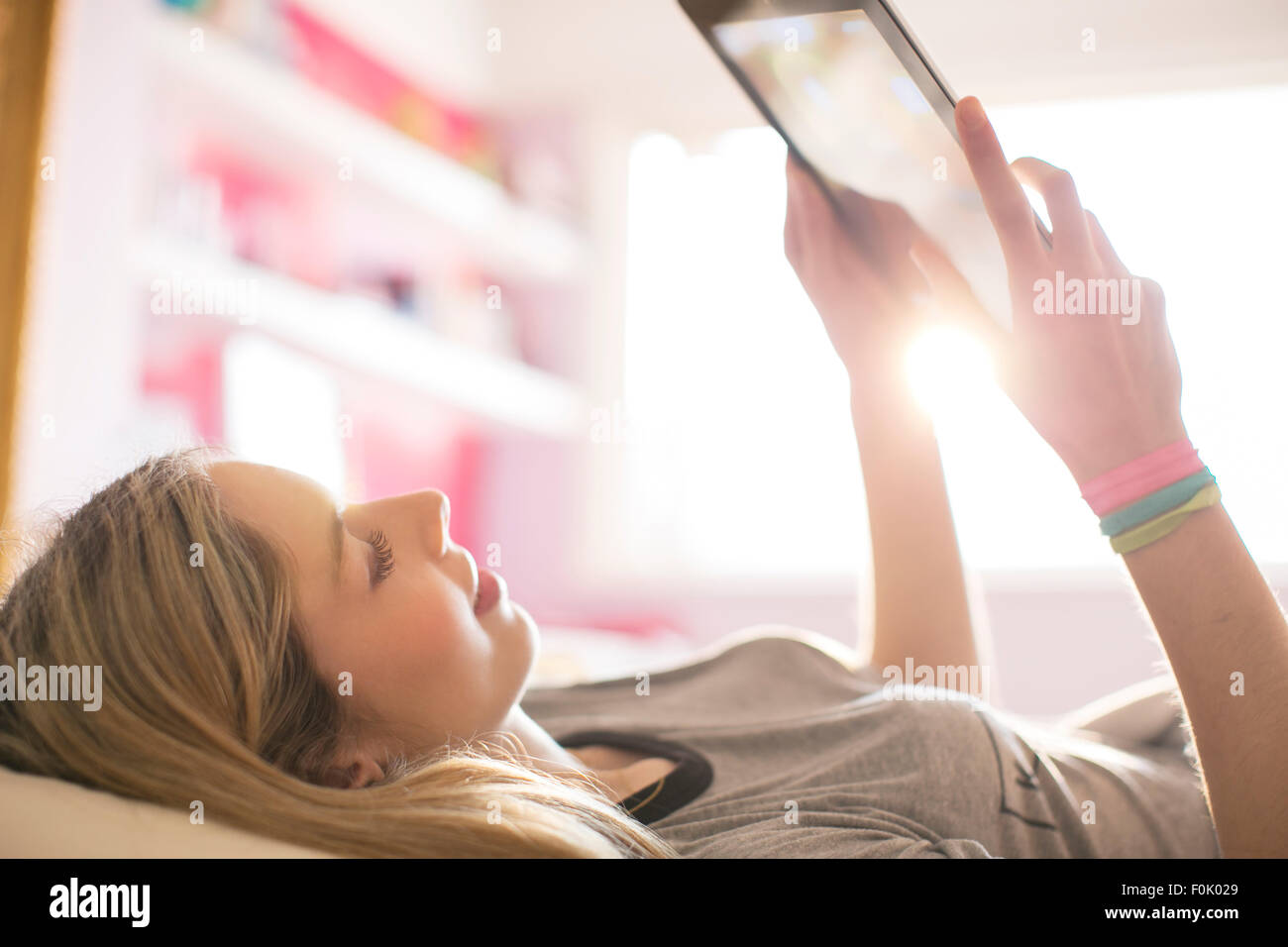 Teenage girl using digital tablet in sunny bedroom Stock Photo - Alamy