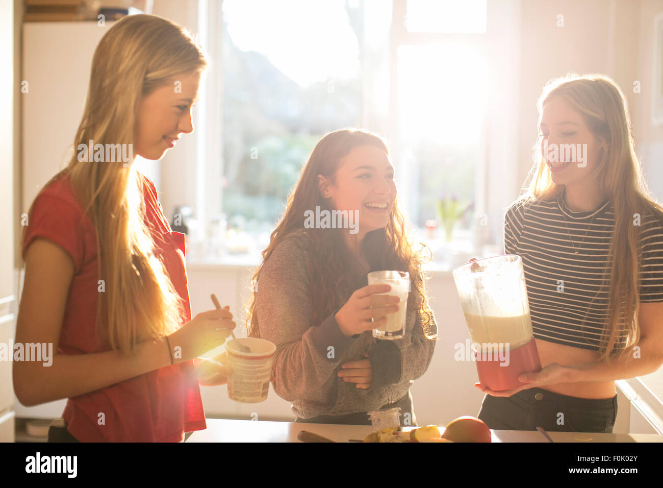 Teenage girls making smoothie in sunny kitchen Stock Photo - Alamy
