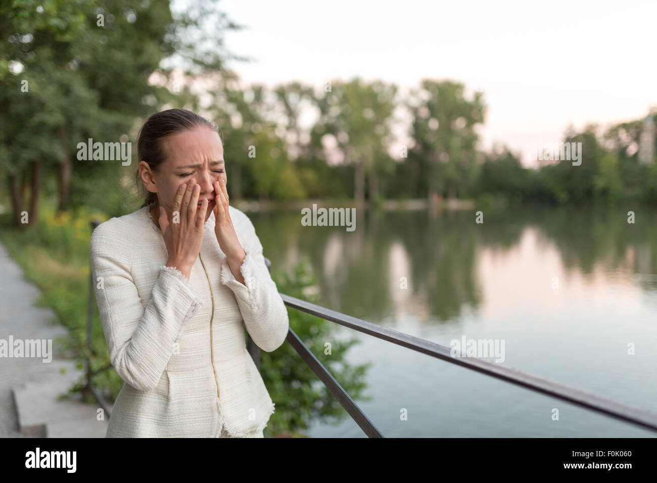 Crying young woman at the harbor next to a railing Stock Photo - Alamy