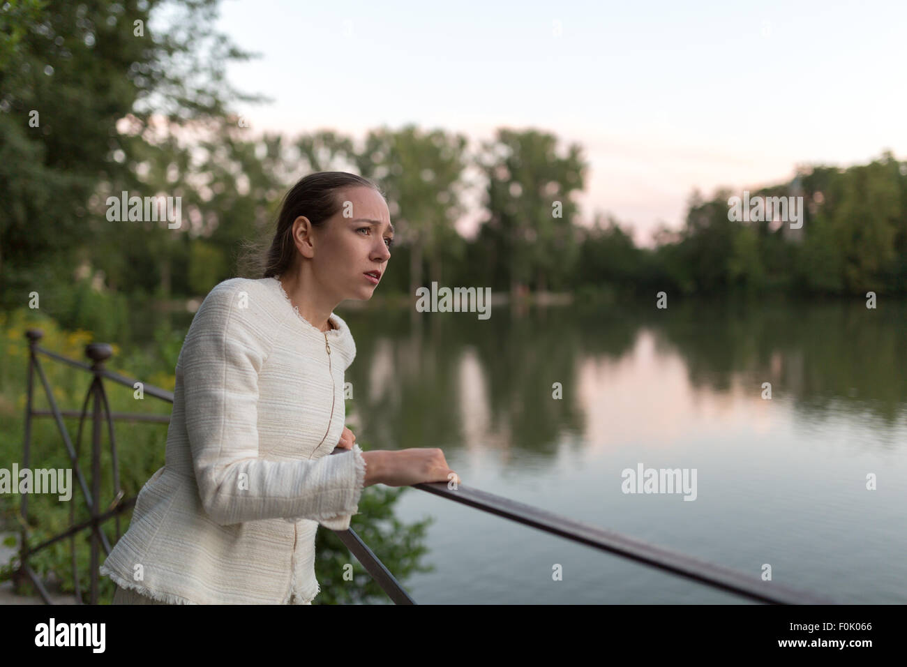 Young woman looking expectant for someone at the harbor leaning over ...