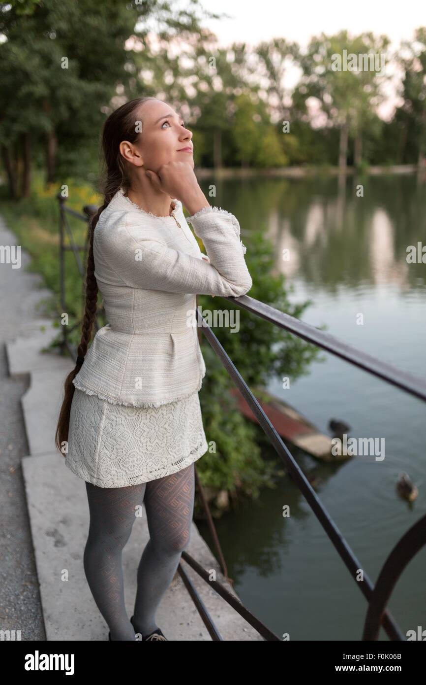 Young merry woman looking happily up to the sky with chin supported by ...