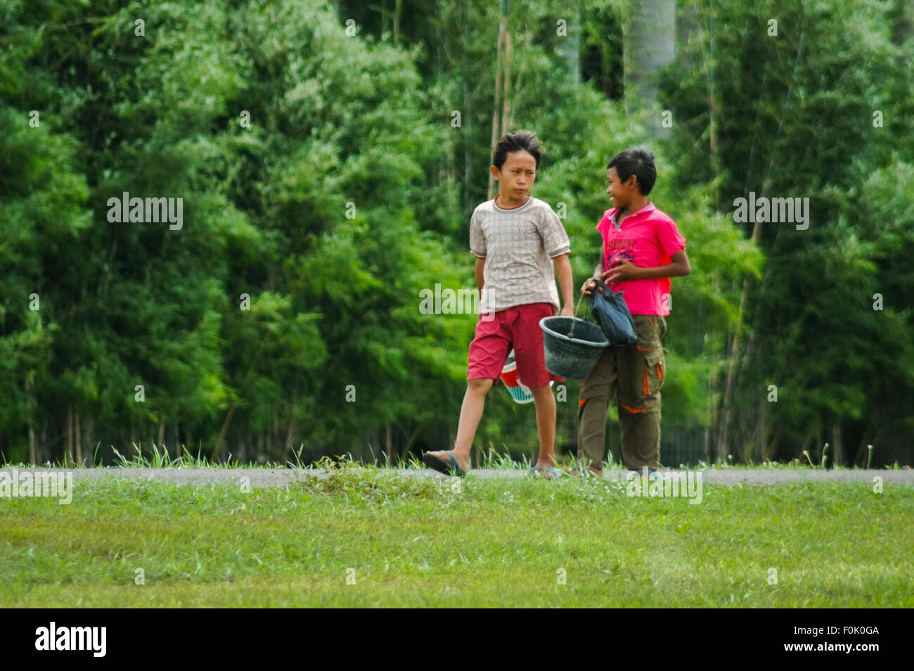 Children carry plastic buckets and have a conversation while walking on ...
