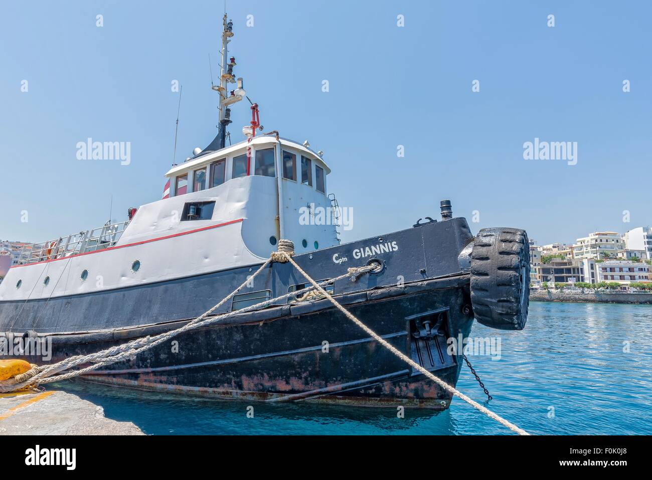 Greek tug boat moored in harbour, with buildings of a town in the ...