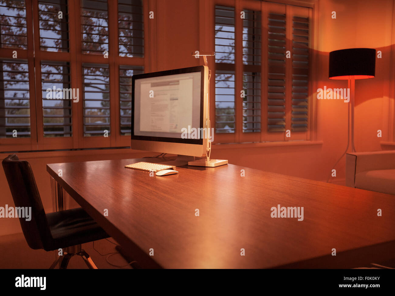 Illuminated lamp behind computer on desk in home office Stock Photo - Alamy