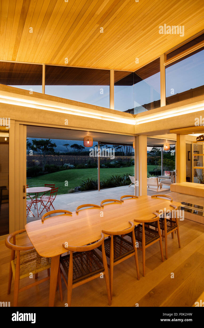 Illuminated slanted wood ceiling over long dining table Stock Photo - Alamy