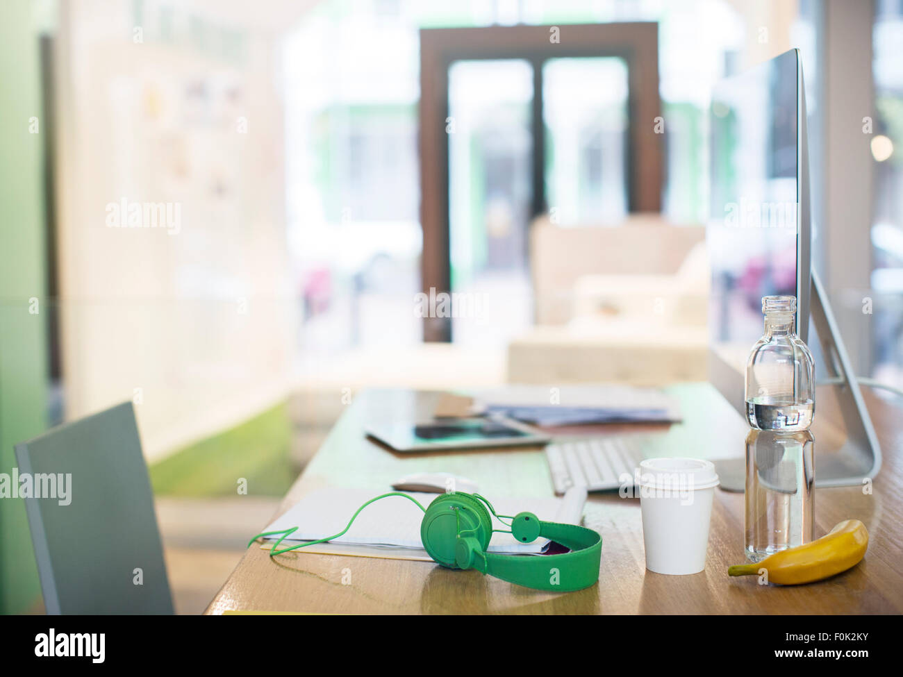 Headphones, water bottle, coffee and banana on desk with computer Stock ...