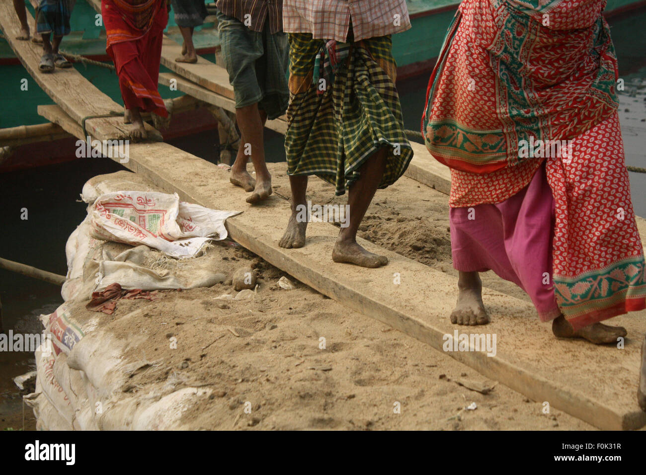 Male and female laborers carry heavy loads of sand balanced on their ...