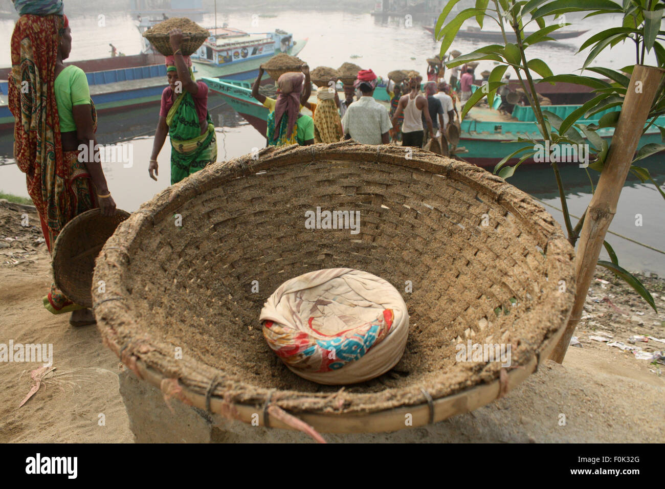 Male and female laborers carry heavy loads of sand balanced on their ...