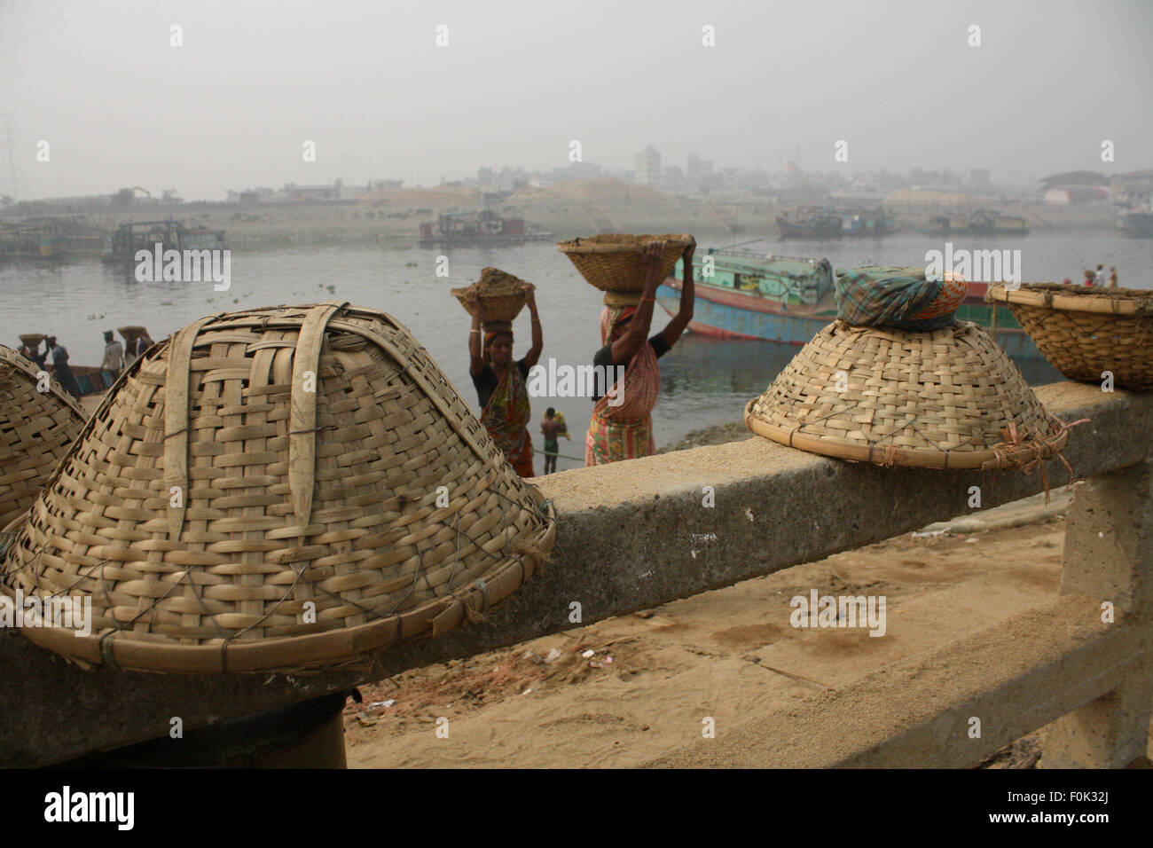 Male and female laborers carry heavy loads of sand balanced on their ...