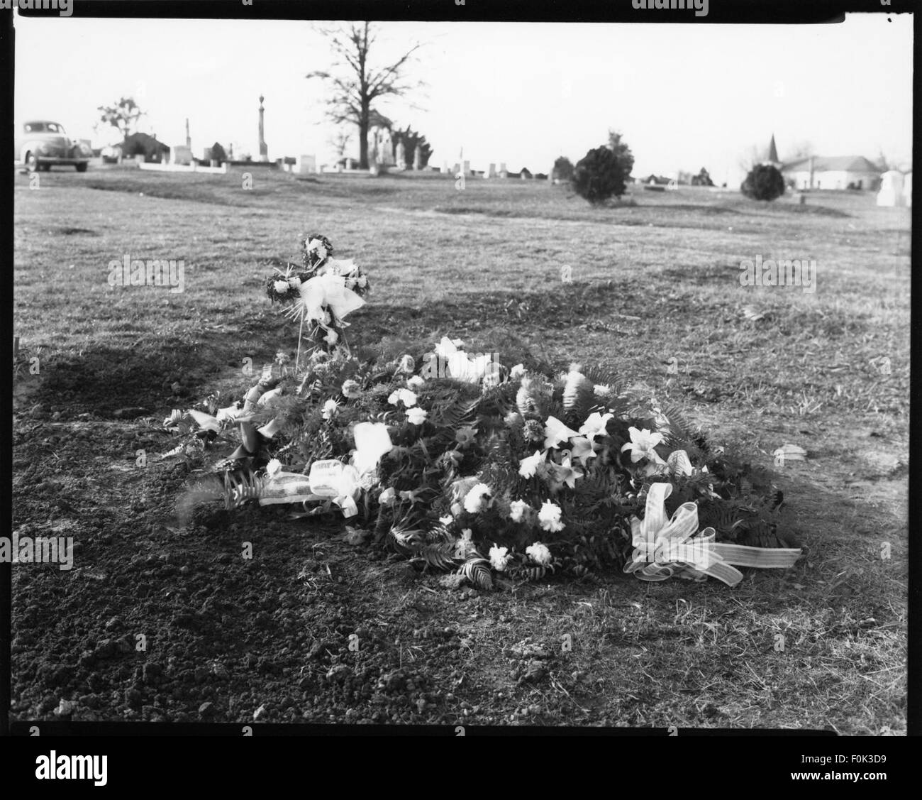 This image depicts a funeral gravesite in a cemetery, marking the final ...
