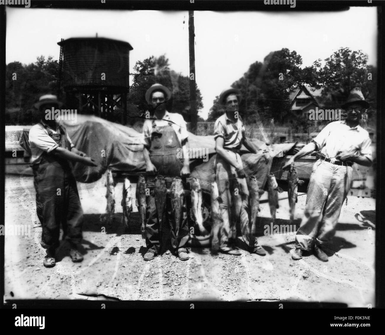 The photograph shows a group of men posing with their catch of fish ...