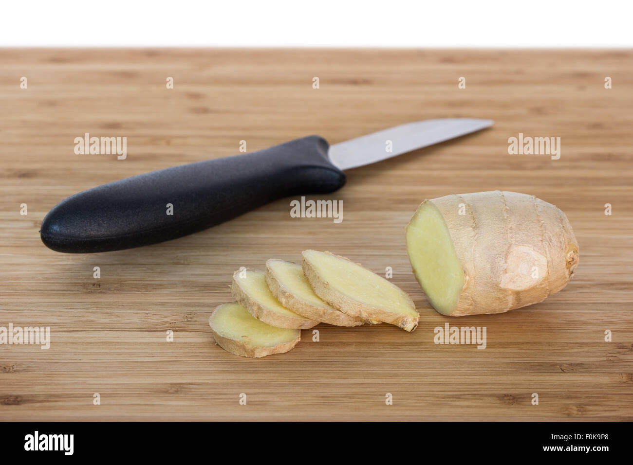 Close-up of a kitchen knife and piece and slices of a fresh ginger root ...