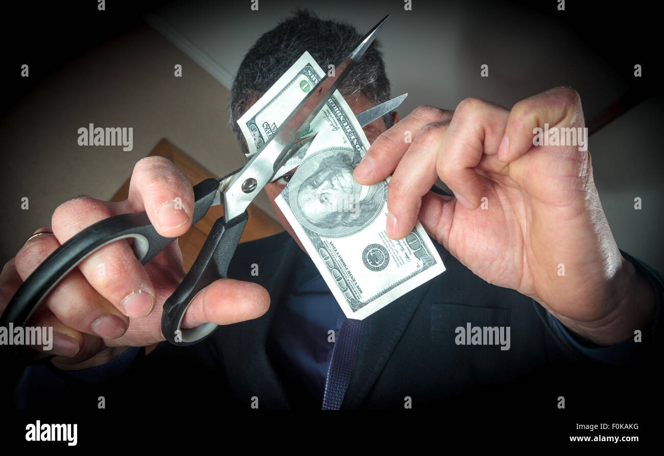 Man with scissors cuts the banknote denominations of 100 dollars ...