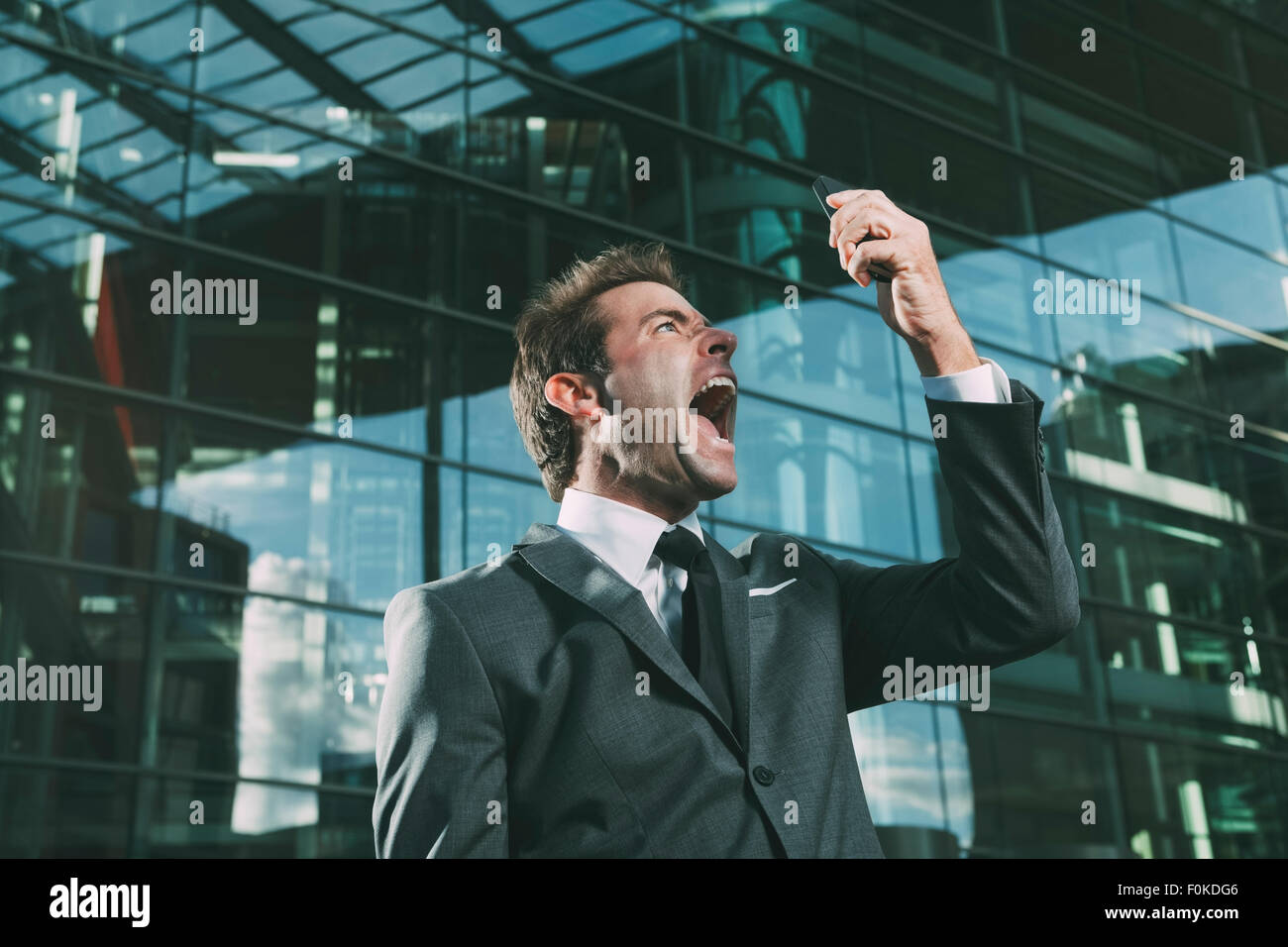 Angry businessman screaming at cell phone outside office building Stock ...