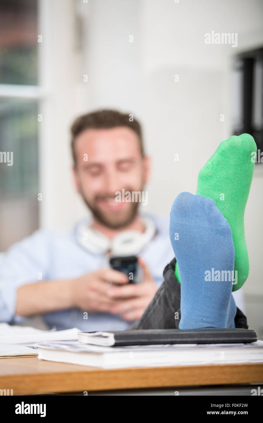 Young man in office with feet on desk wearing different socks Stock ...