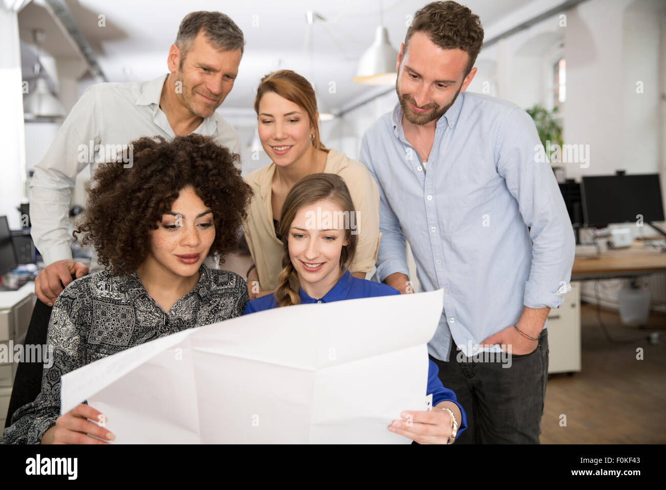 Colleagues in office looking at plan Stock Photo - Alamy