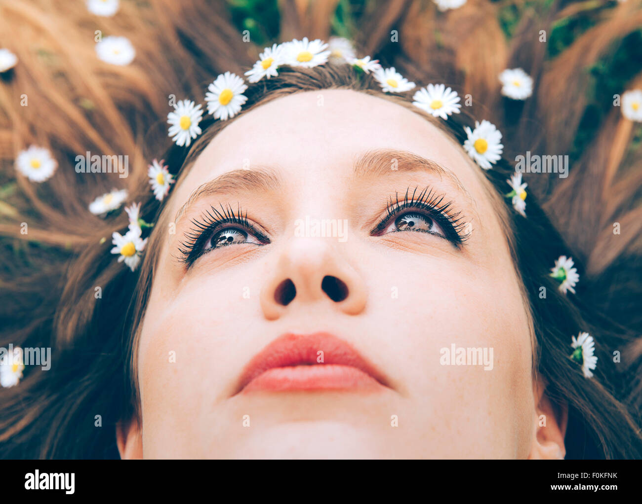 Young Woman Lying On Grass With Daisies In The Hair Close Up Stock