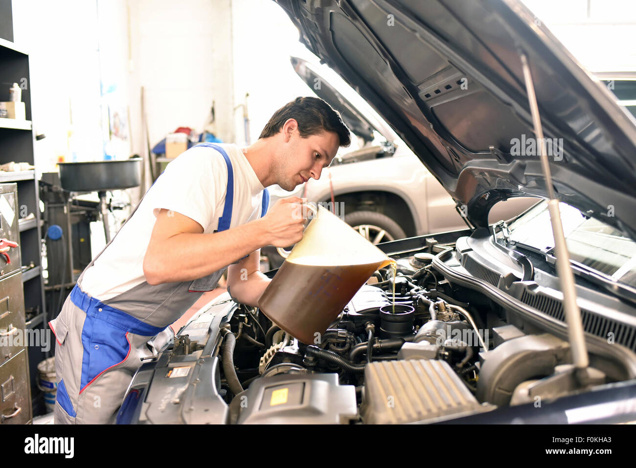 Car mechanic refilling engine oil Stock Photo - Alamy