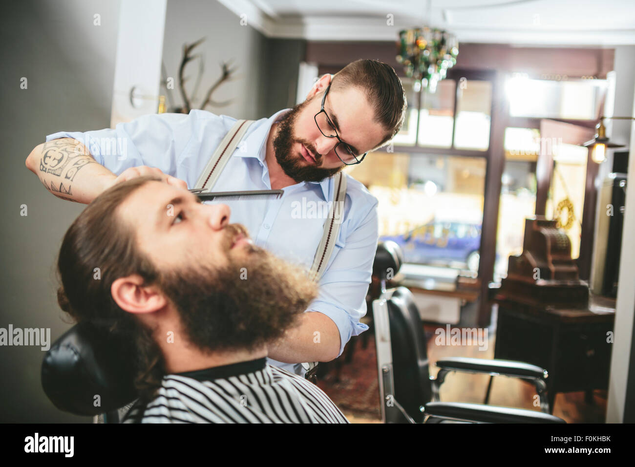 Barber cutting beard of a customer Stock Photo - Alamy