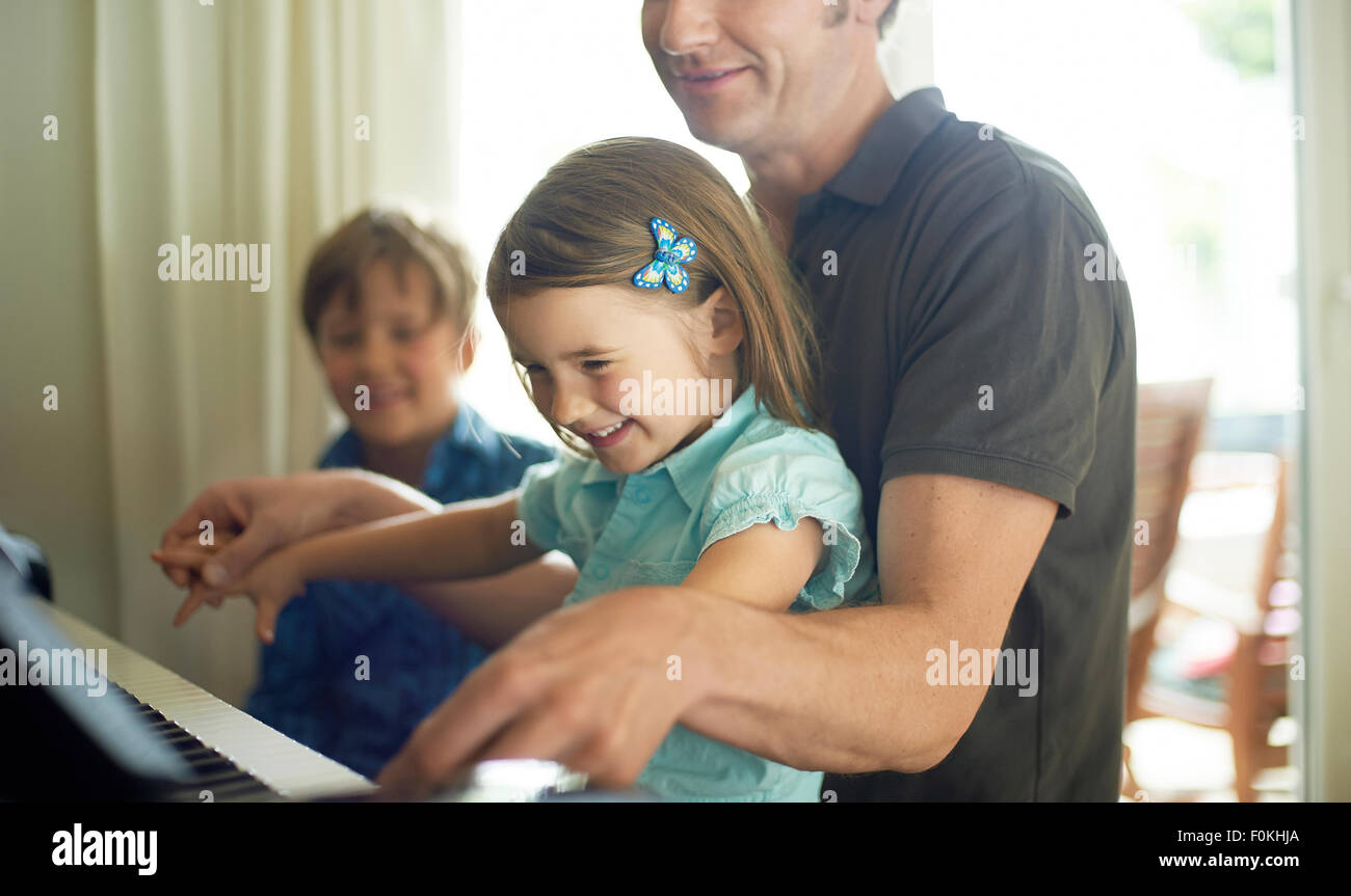 Father playing piano with daughter on his lap, son watching Stock Photo ...