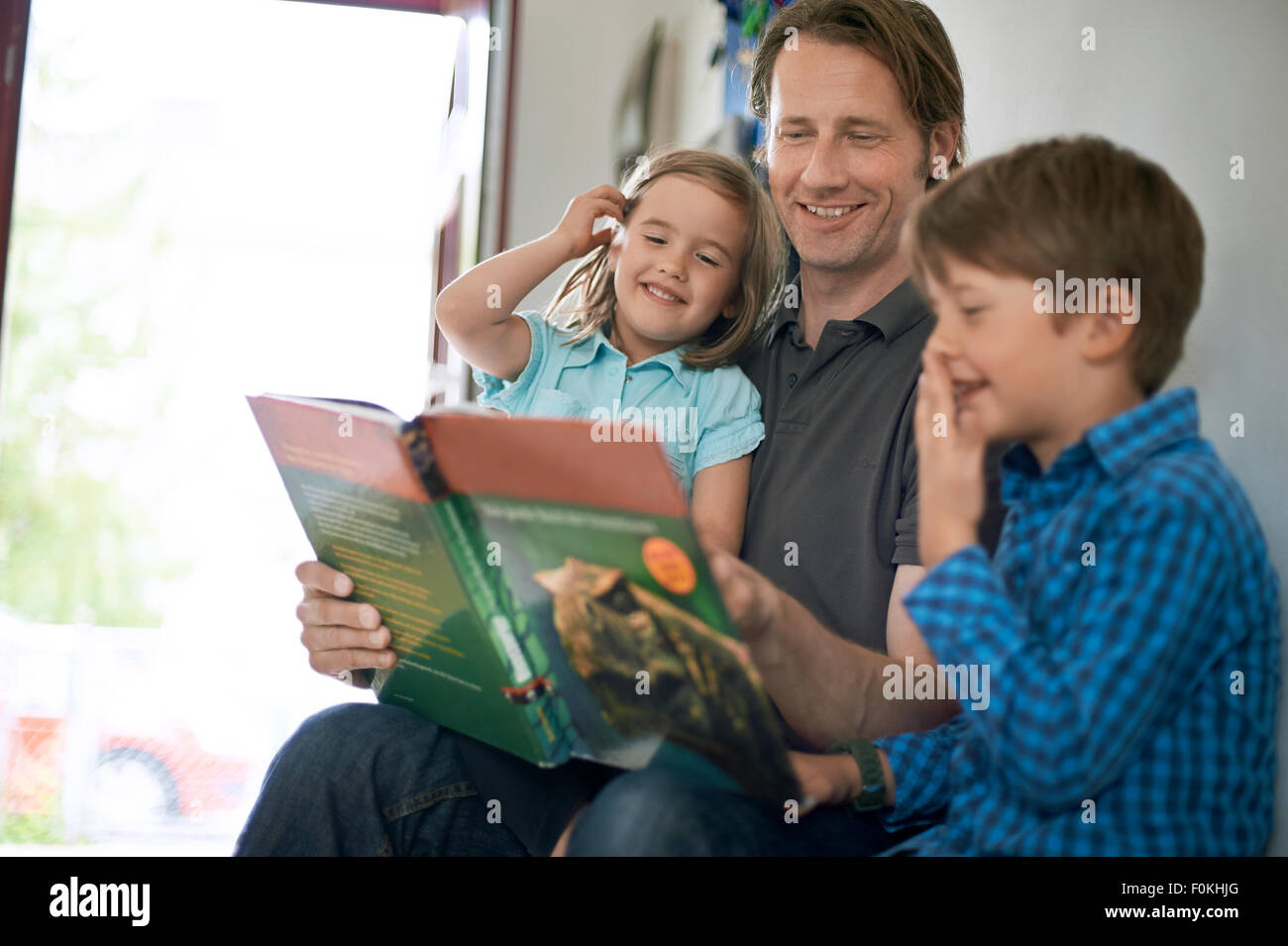 Father reading out book to his children Stock Photo - Alamy