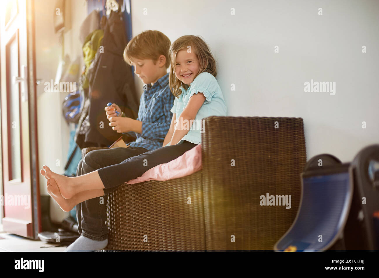 Brother and sister sitting on bench at home, having fun Stock Photo - Alamy