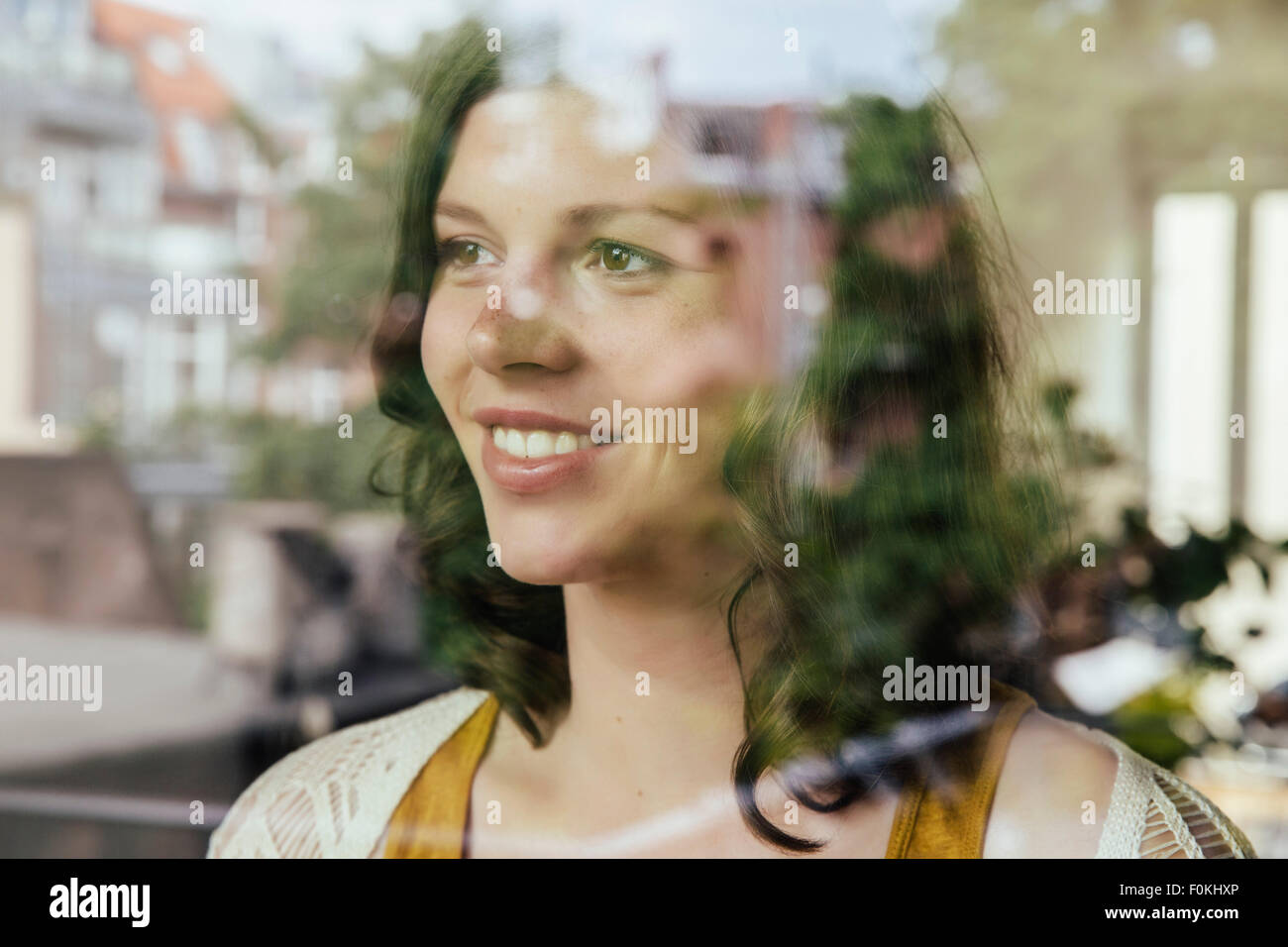 Portrait of woman looking through the window Stock Photo - Alamy