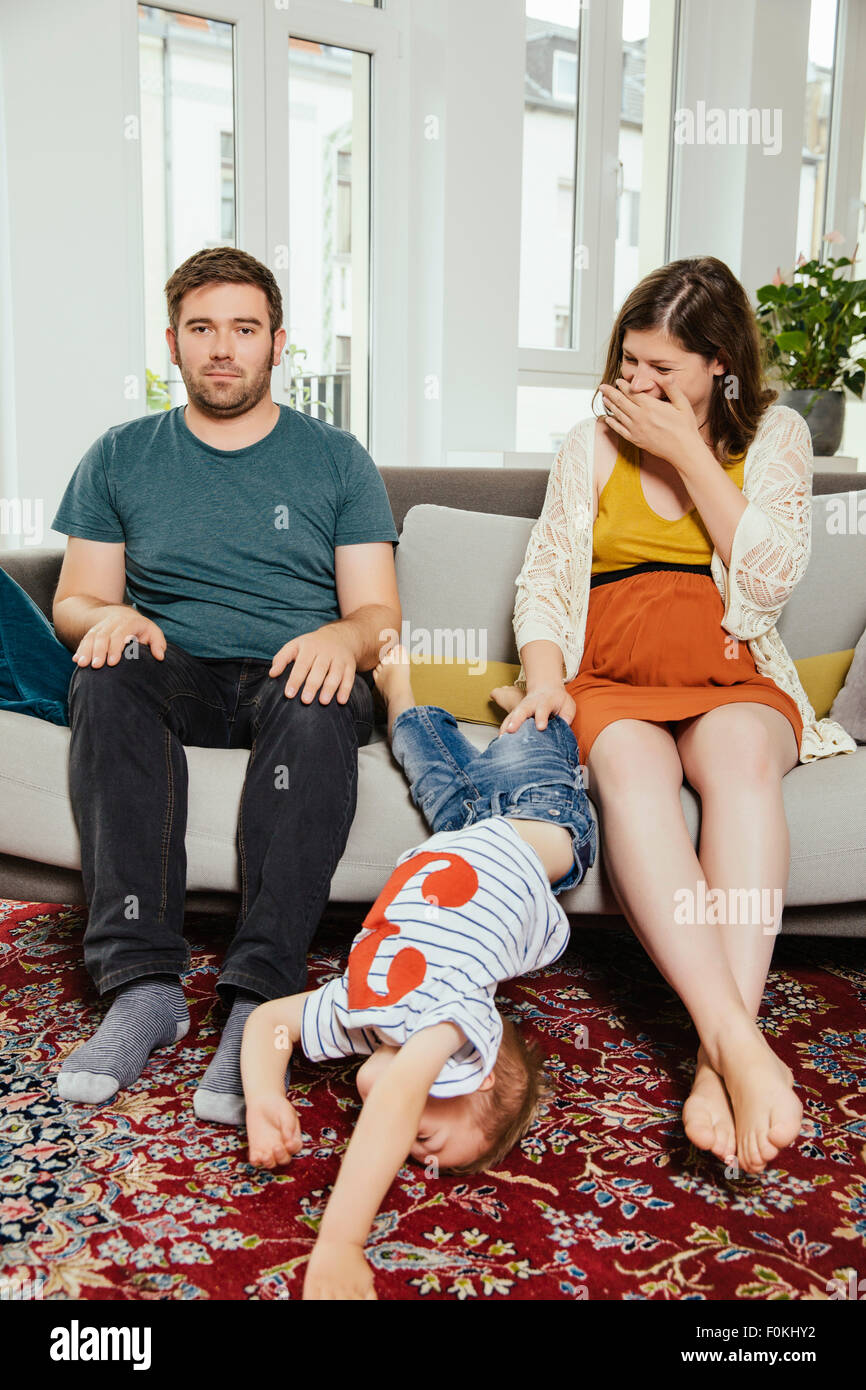 Disturbed family portrait on a sofa at home with son jumping away Stock ...