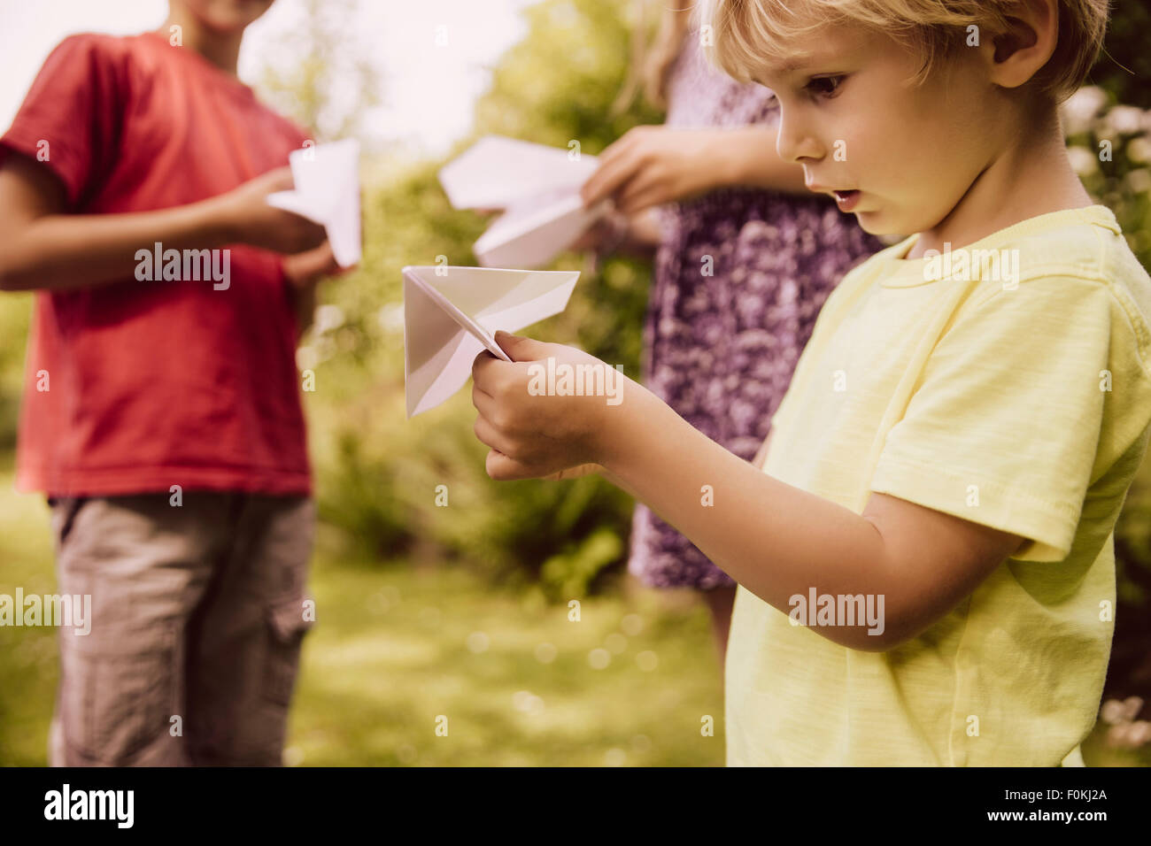 Three children playing with paper planes in garden Stock Photo - Alamy