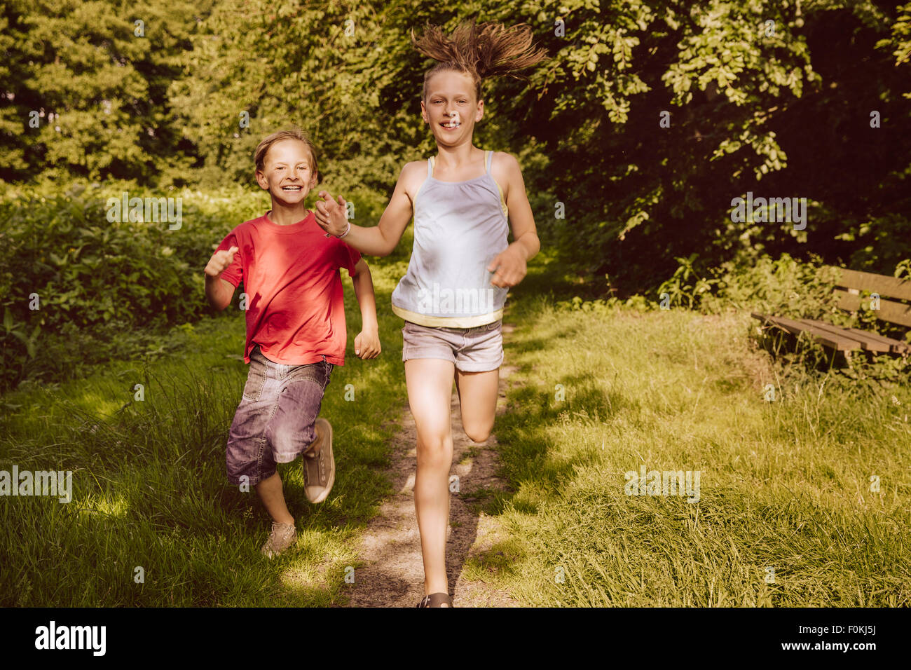Girl and boy running along path in nature Stock Photo - Alamy