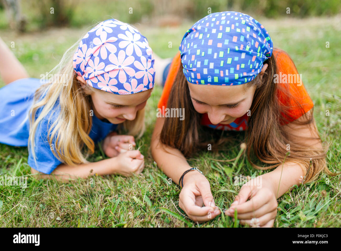 Two little sisters lying on a meadow Stock Photo - Alamy