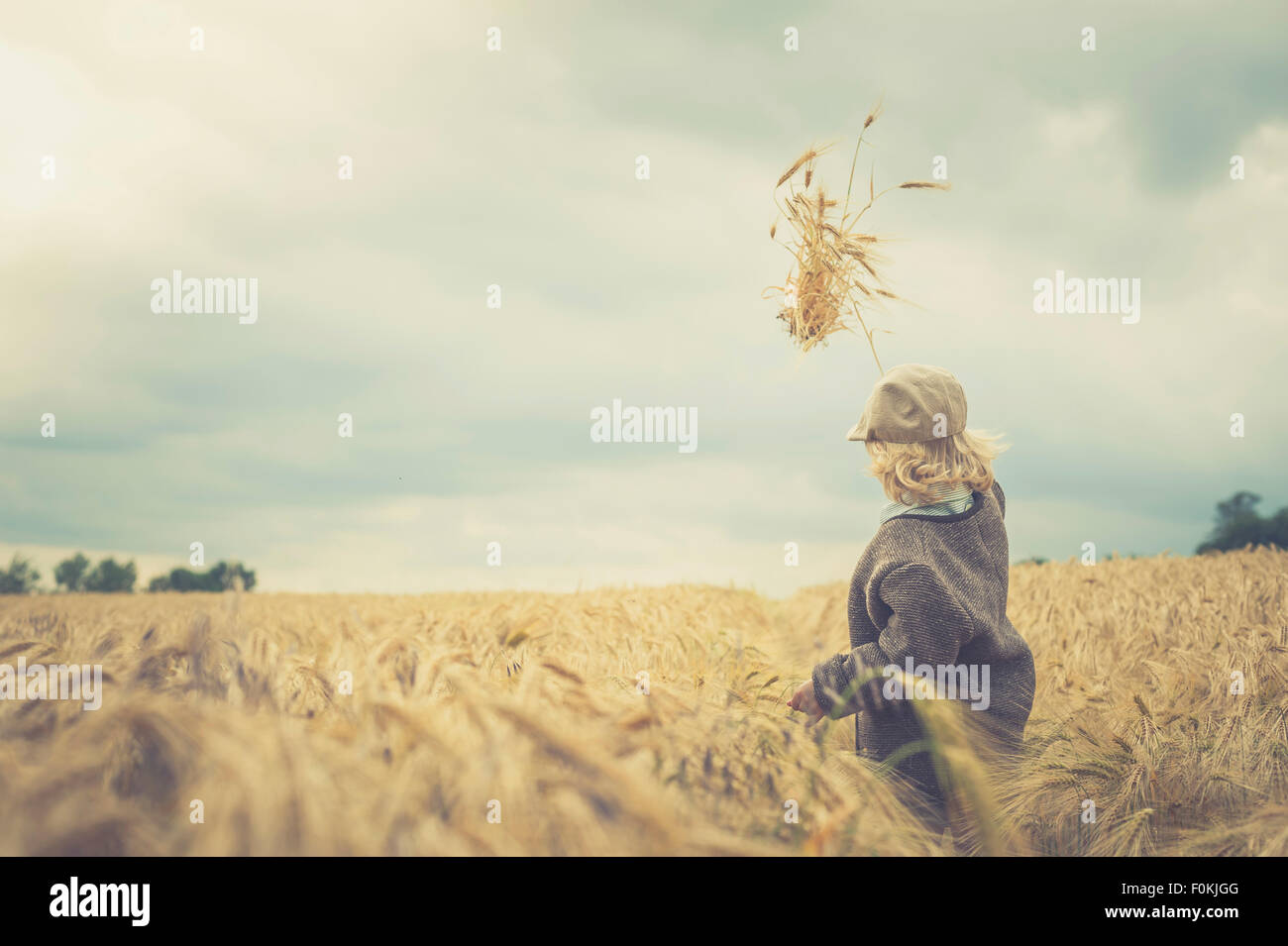 Back view of little boy standing in a field throwing spikes in the air ...
