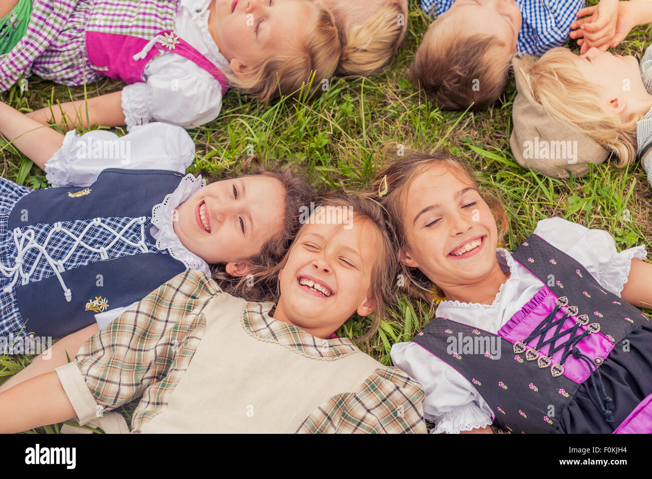 Germany, Saxony, group of children wearing traditional clothes lying on ...