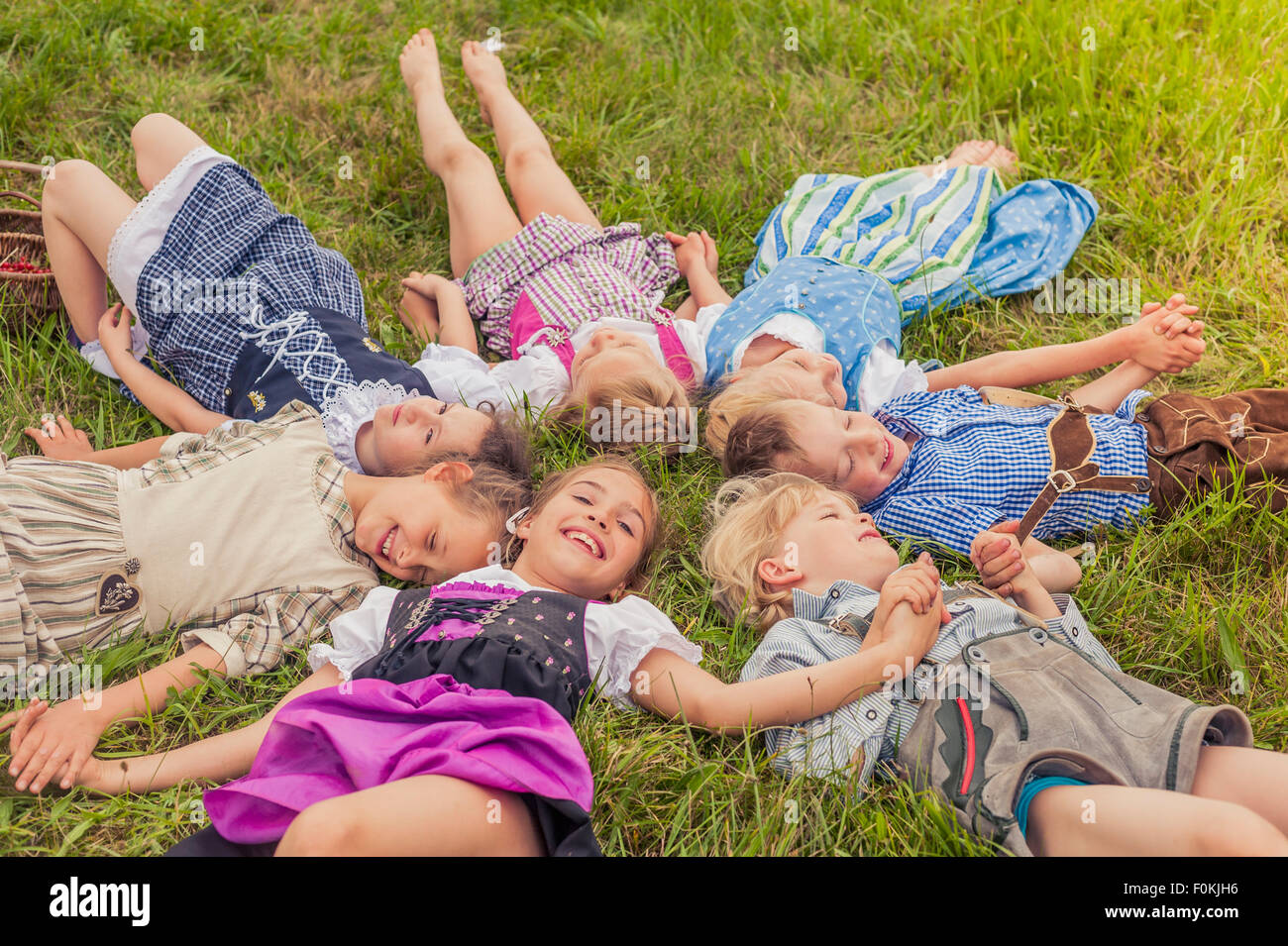Germany, Saxony, group of children wearing traditional clothes lying on ...