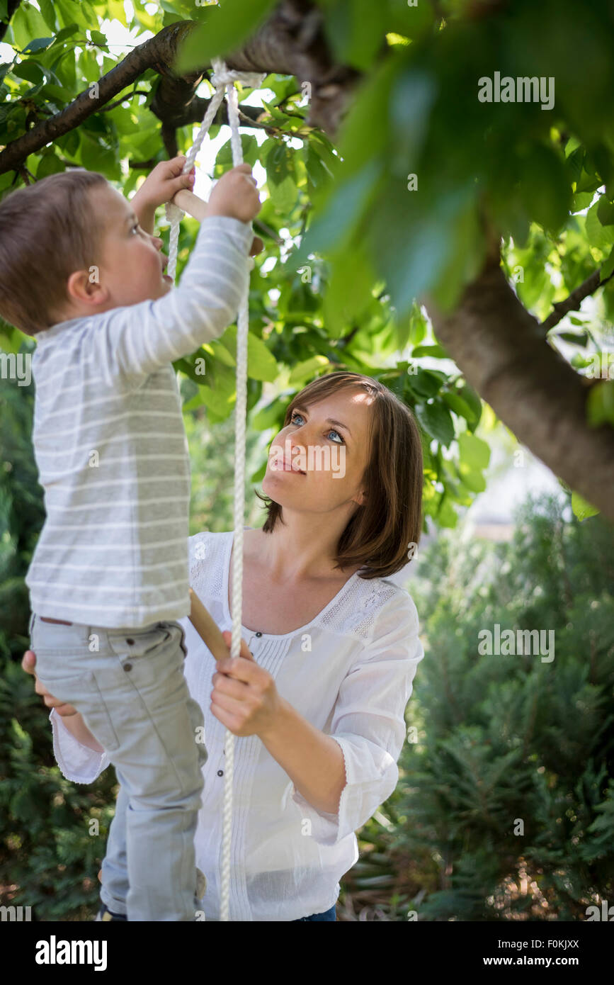 Mother helping her little son climbing up a rope ladder Stock Photo - Alamy