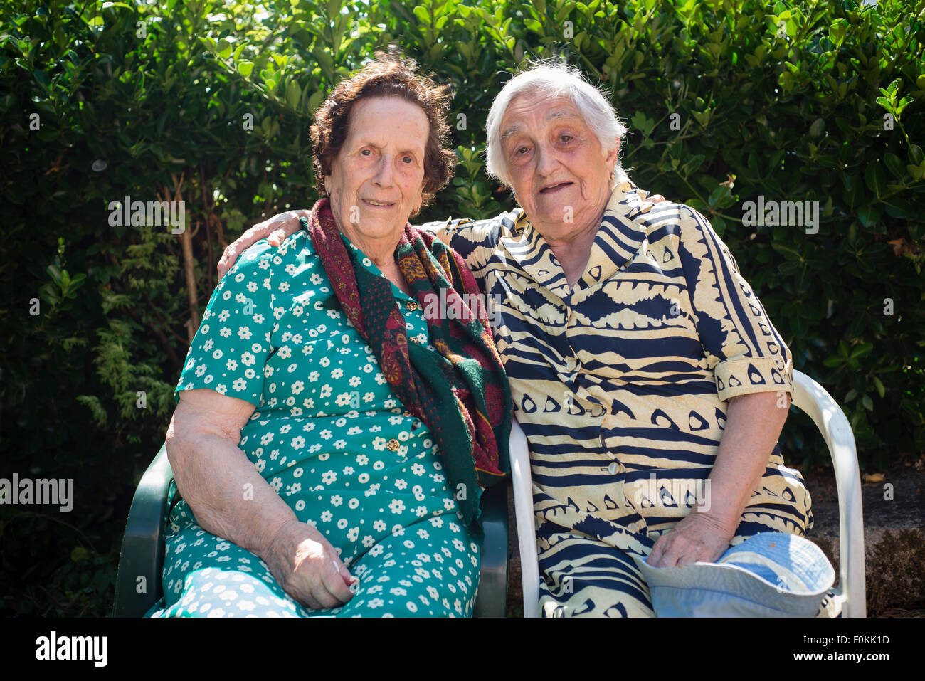 Portrait of two senior women sitting side by side on chairs in the ...