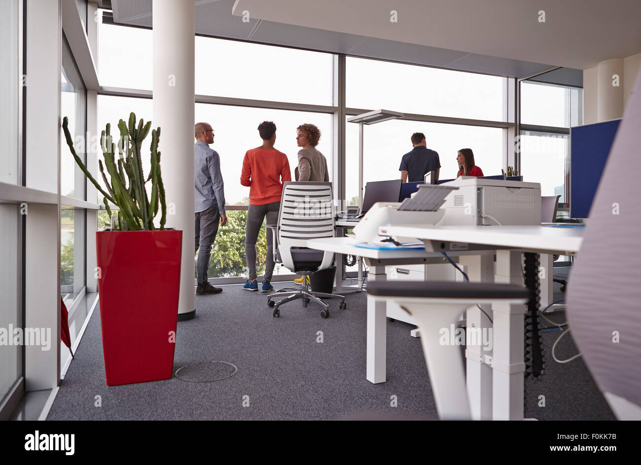 Colleagues in open-plan office standing at the window Stock Photo - Alamy