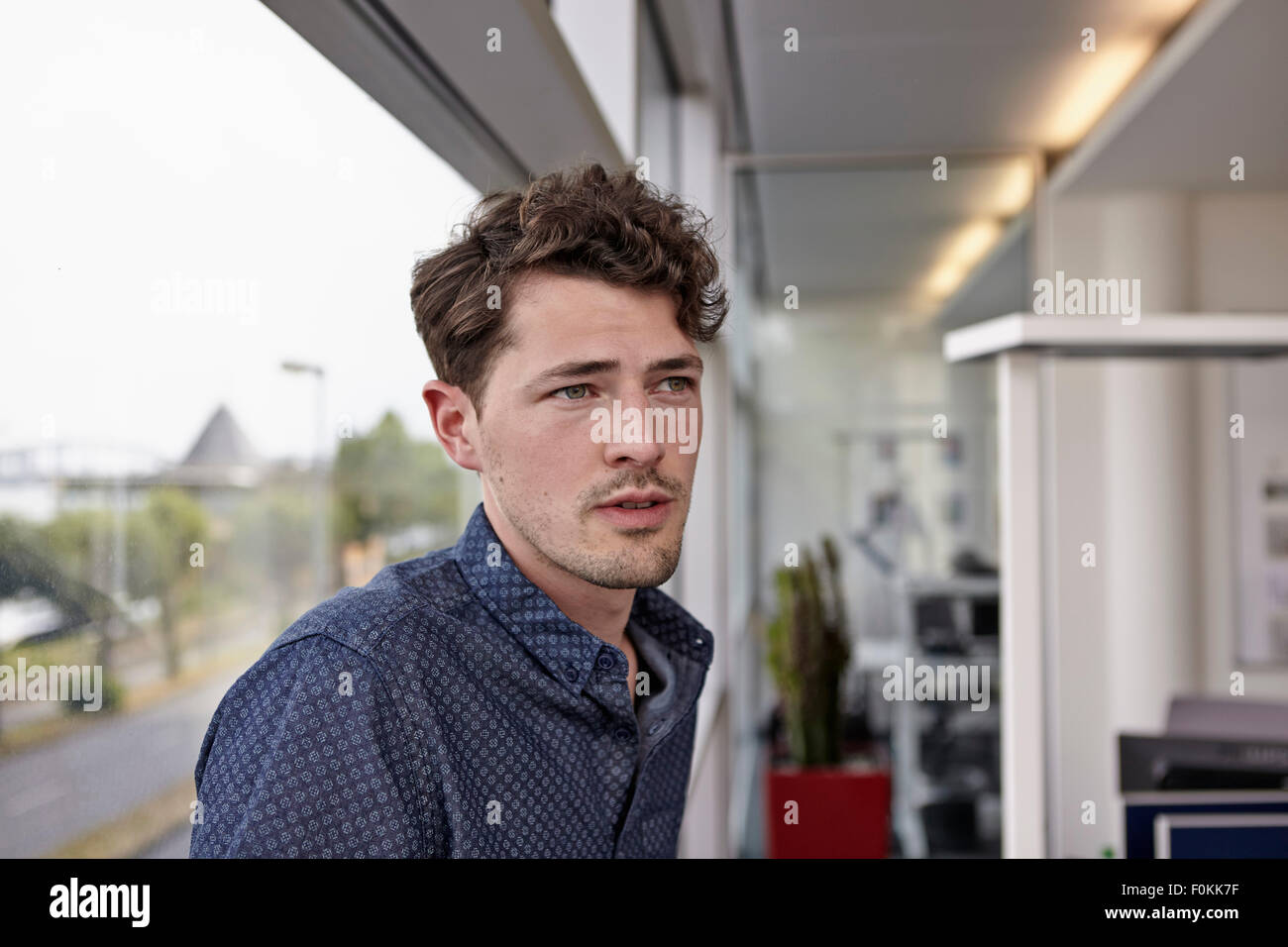 Young man in office at the window Stock Photo - Alamy