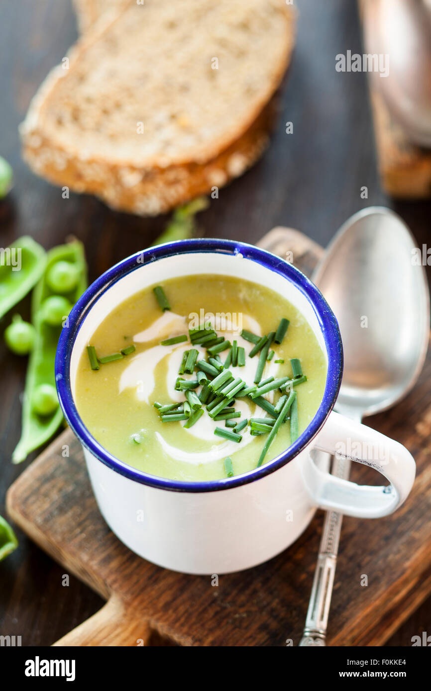 Enamel cup of pea soup with chives Stock Photo - Alamy