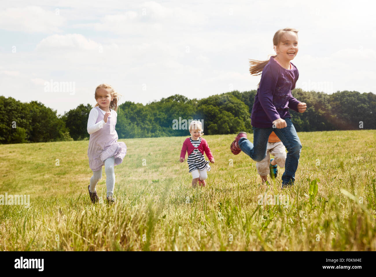 Four little children running on a meadow Stock Photo - Alamy