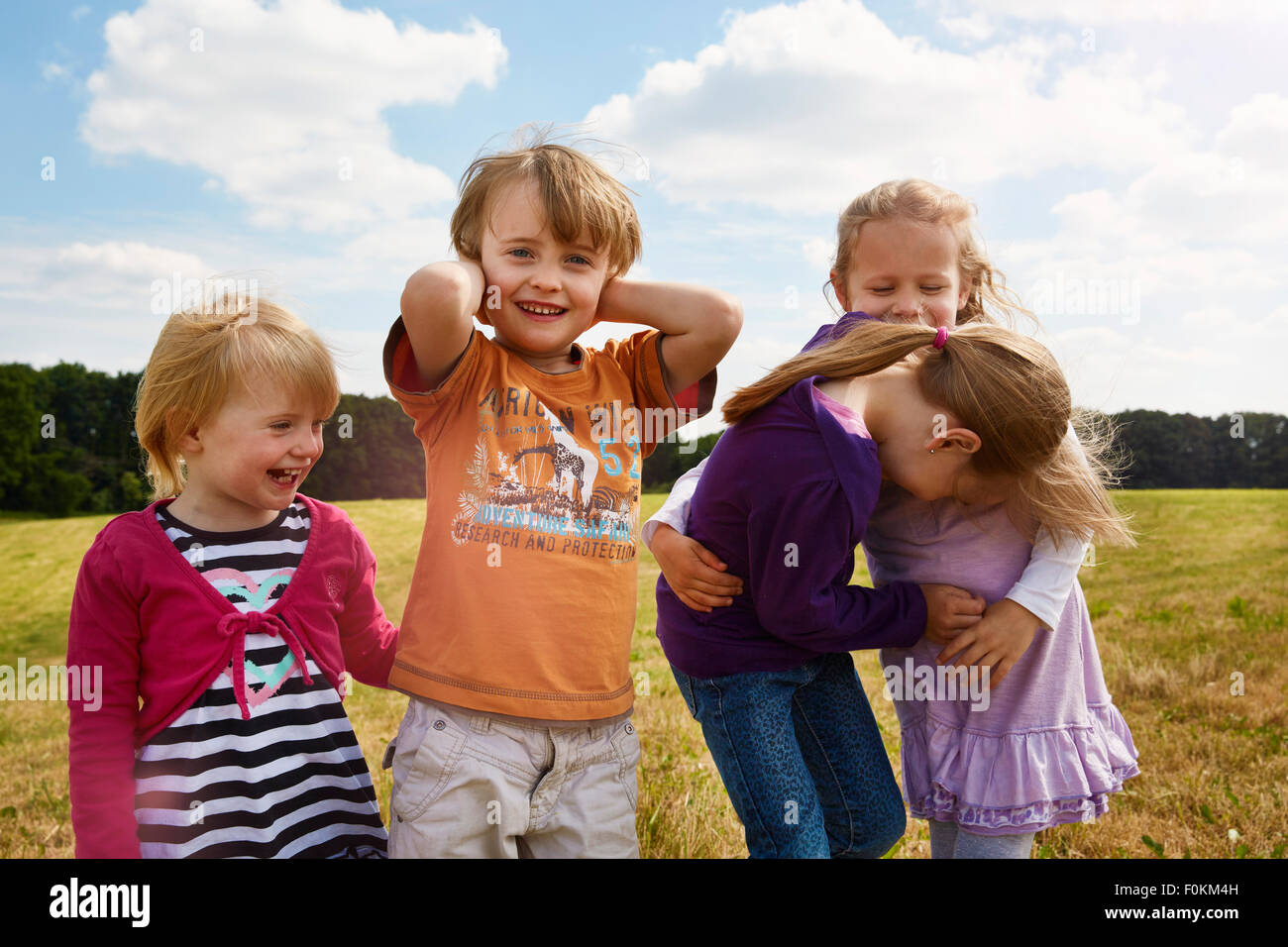 Four little children playing on a meadow Stock Photo - Alamy