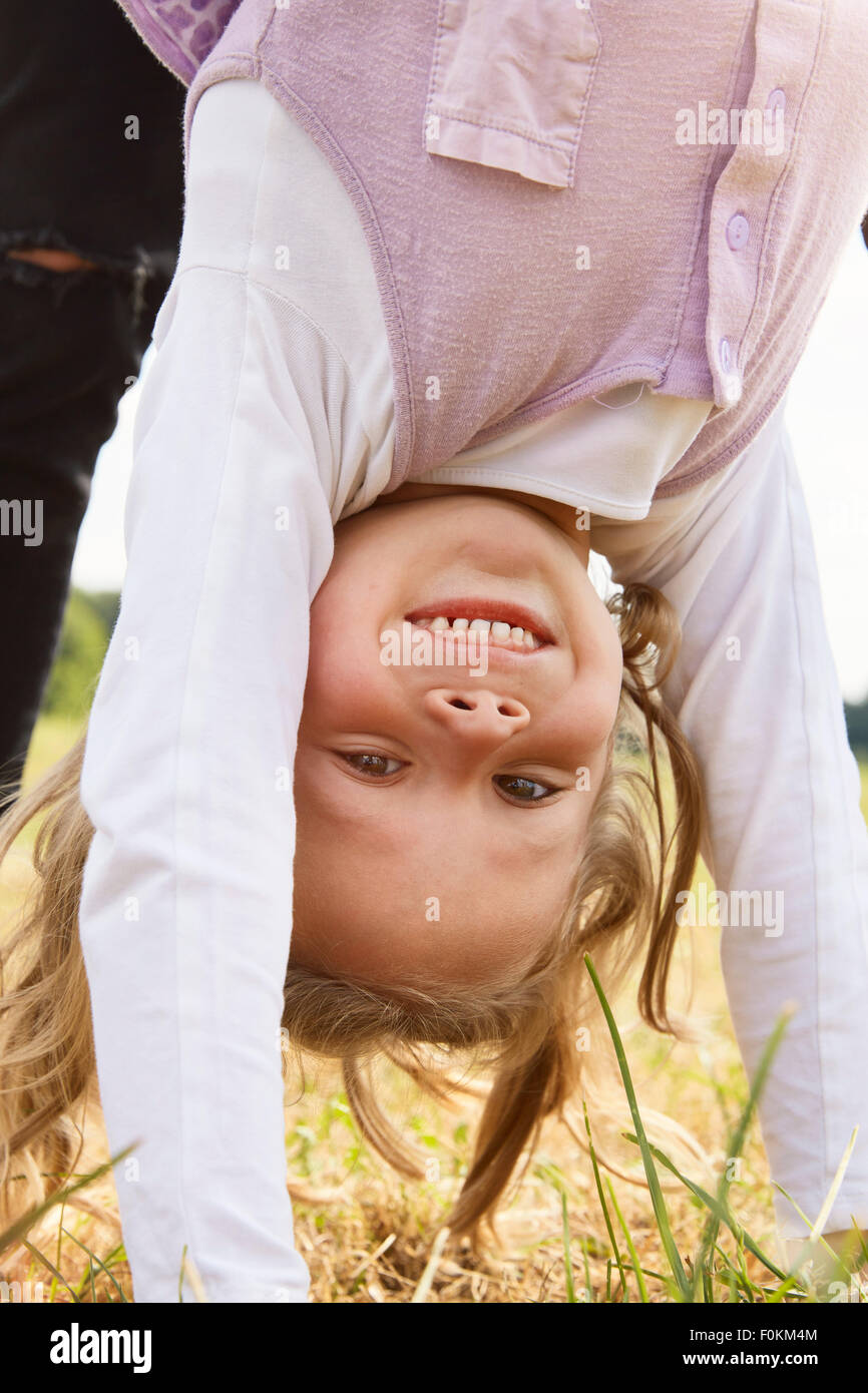 Portrait of happy little girl doing handstand on a meadow Stock Photo ...