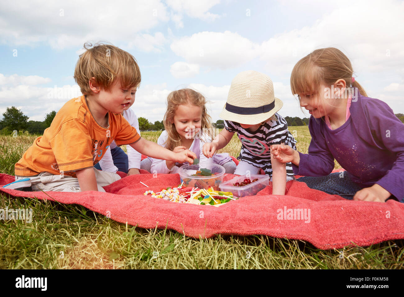Children sitting on a blanket choosing sweets Stock Photo - Alamy
