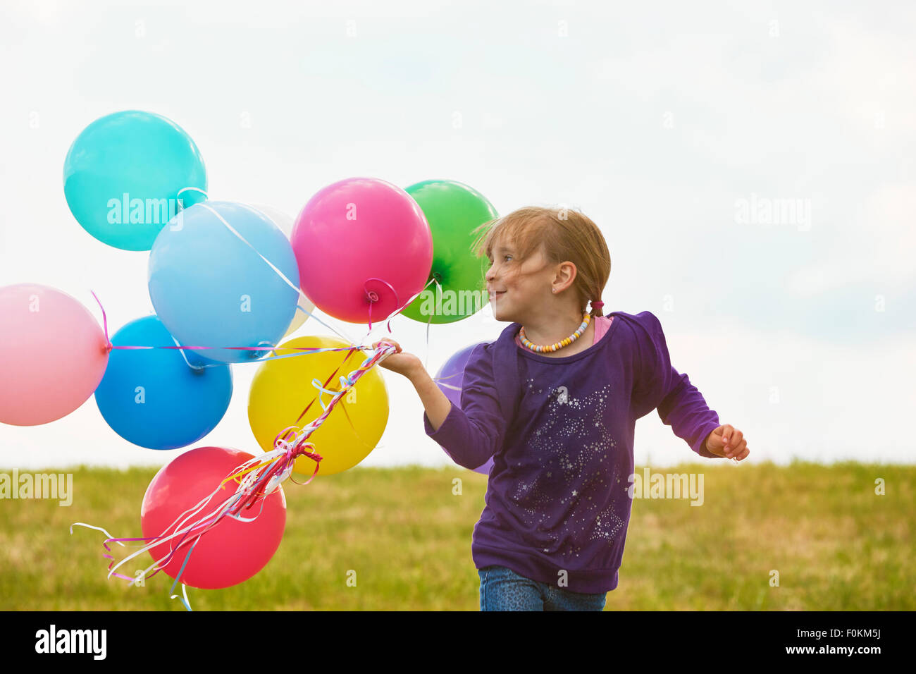 Little girl with balloons running on a meadow Stock Photo - Alamy