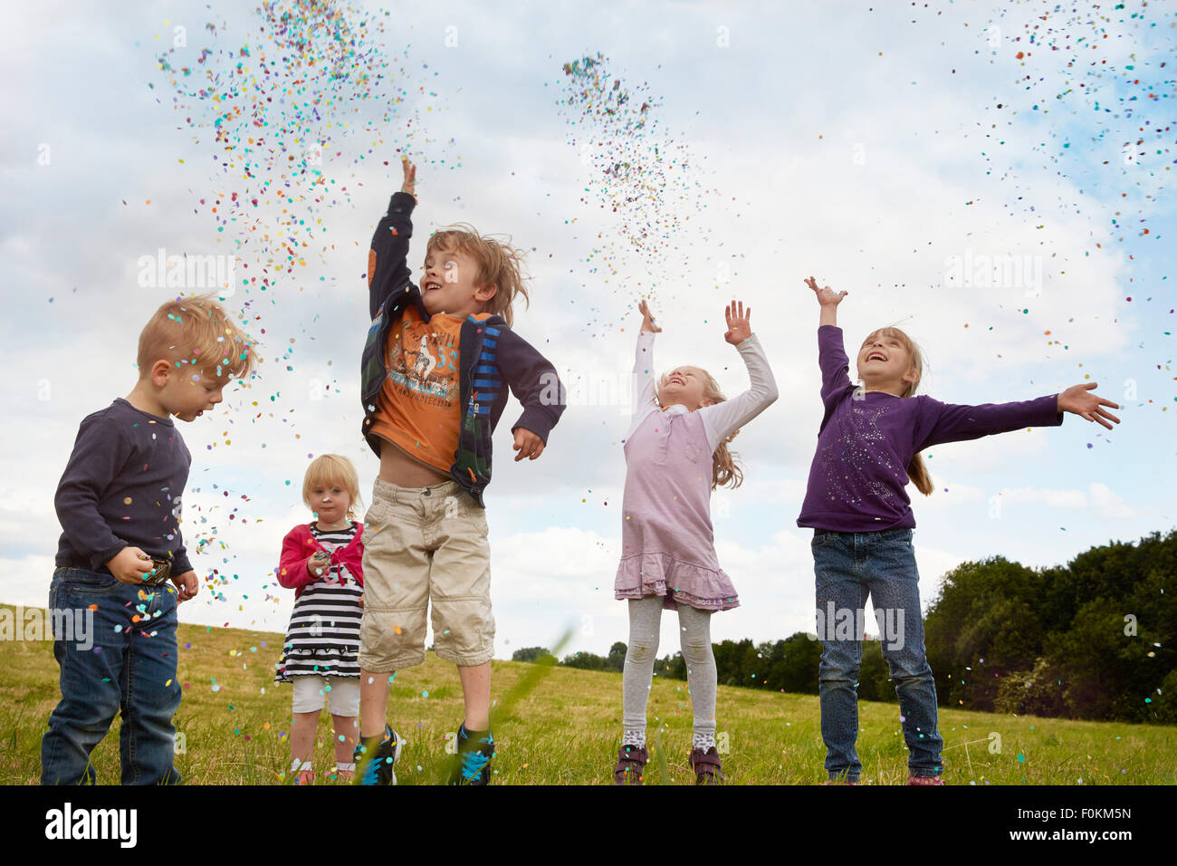 Five little children throwing confetti on a meadow Stock Photo - Alamy